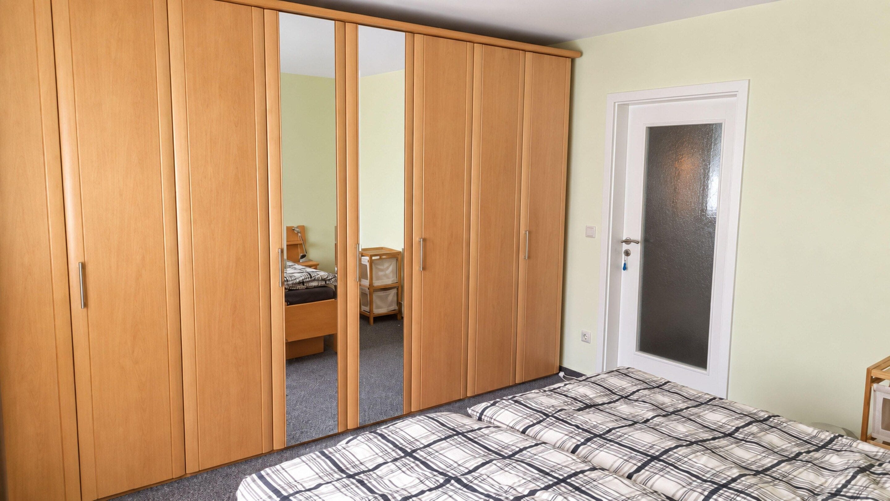 Quarto com cama, guarda-roupa e porta.