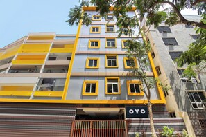Um edifício de vários andares com fachada amarela e cinza, várias janelas e uma placa com a inscrição 'OYO'.