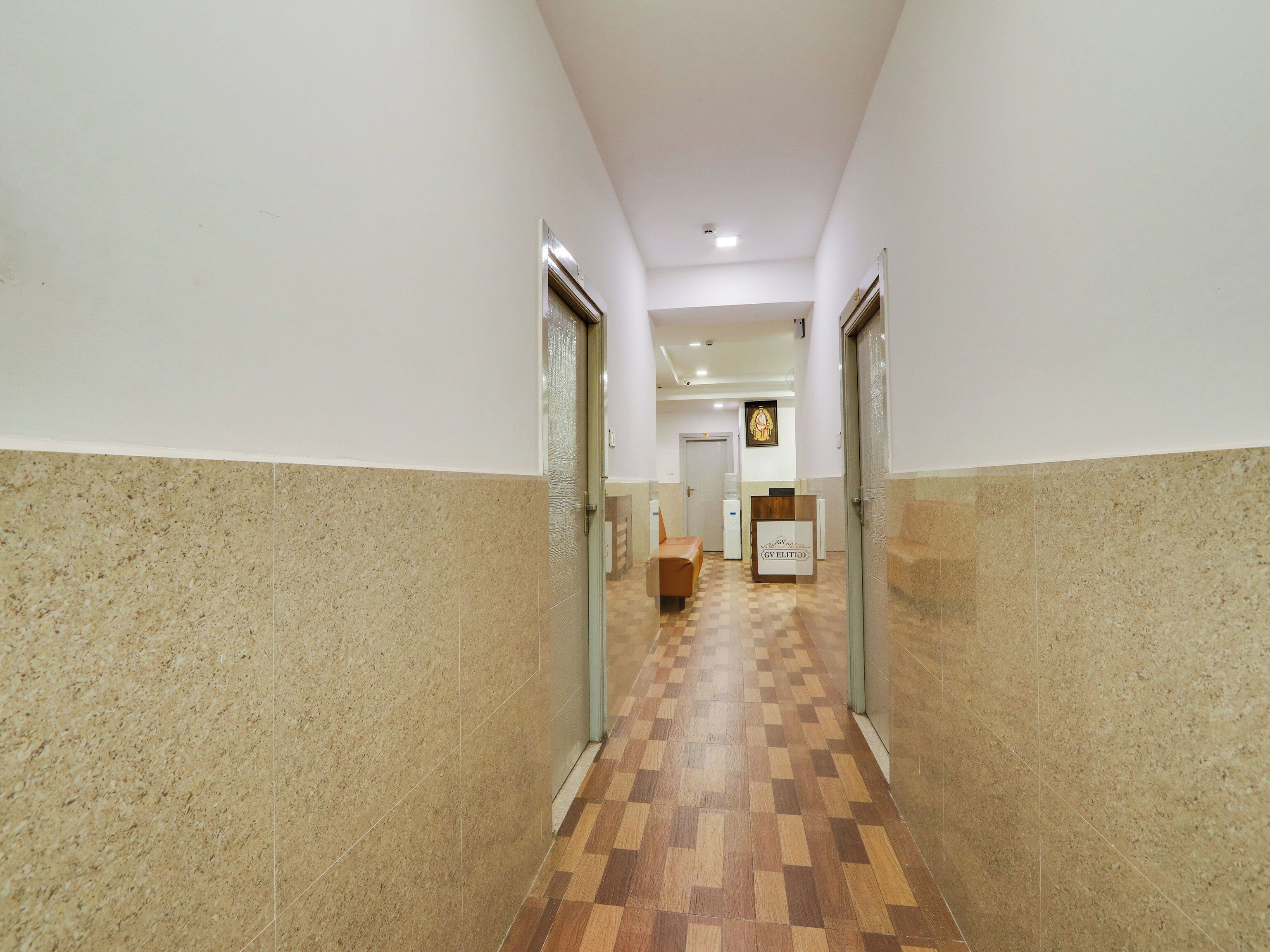 Um corredor com piso xadrez, balcão de recepção e uma porta no final.