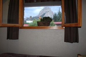 Janela com vista para uma montanha e um edifício.