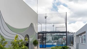 Um edifício moderno com fachada curva, janelas amplas e vista para a paisagem urbana.