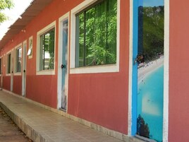 Um edifício com fachada vermelha, várias janelas e uma porta com um mural de uma cena de praia.