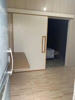 Quarto com closet porta deslizante, cama com colcha estampada e piso ladrilhado.