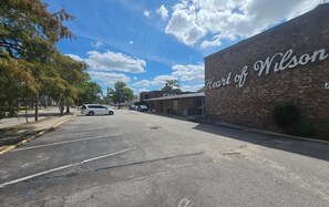Um estacionamento com um edifício de tijolos identificado como 'Heart of Wilson' e céu claro.
