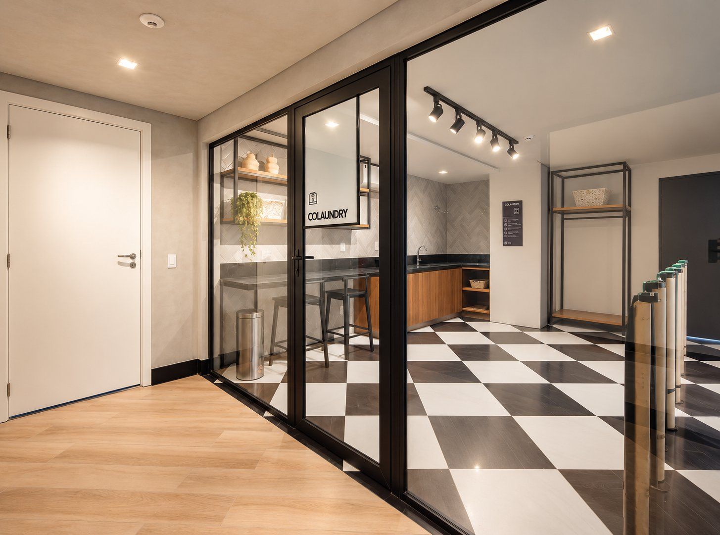 Um interior moderno com piso xadrez, divisória de vidro e placa visível 'COLAUNDRY'.
