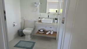 Casa de banho com sanita, lavatório e suporte para toalhas.