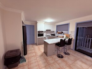 Cozinha compacta com ilha central, banquetas e área de refeições.
