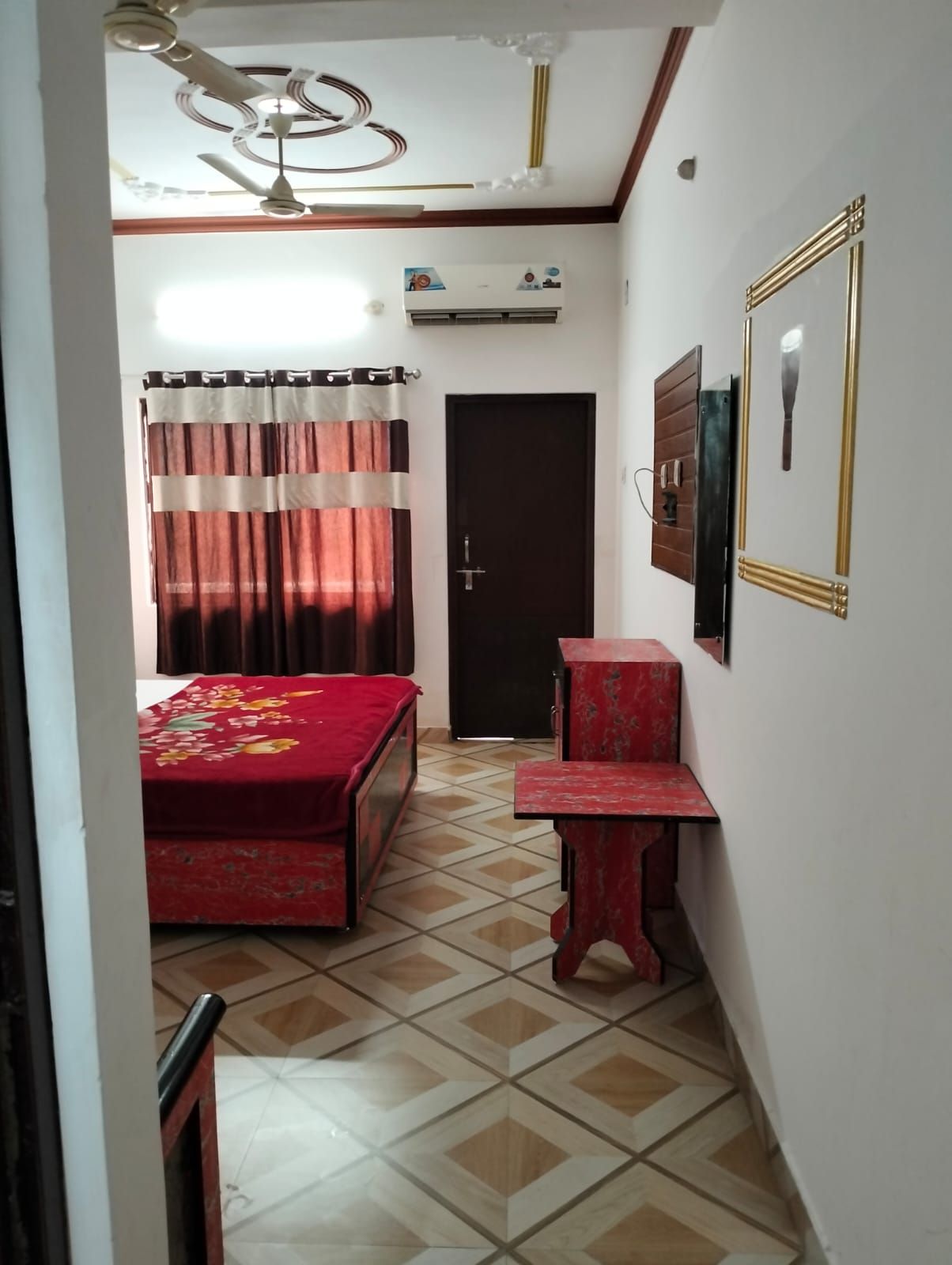 Quarto com cama, escrivaninha, espelho e ventoinha no teto.