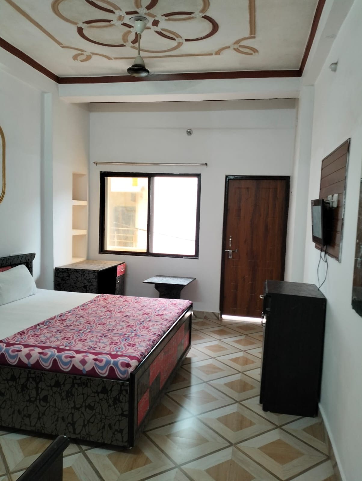 Quarto com cama, janela, porta e televisão.