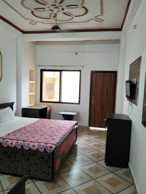 Quarto com cama, janela, porta e televisão.