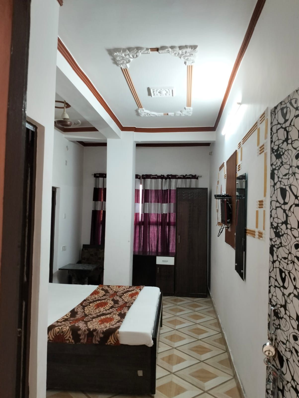 Quarto com cama, guarda-roupa, escrivaninha e papel de parede estampado.