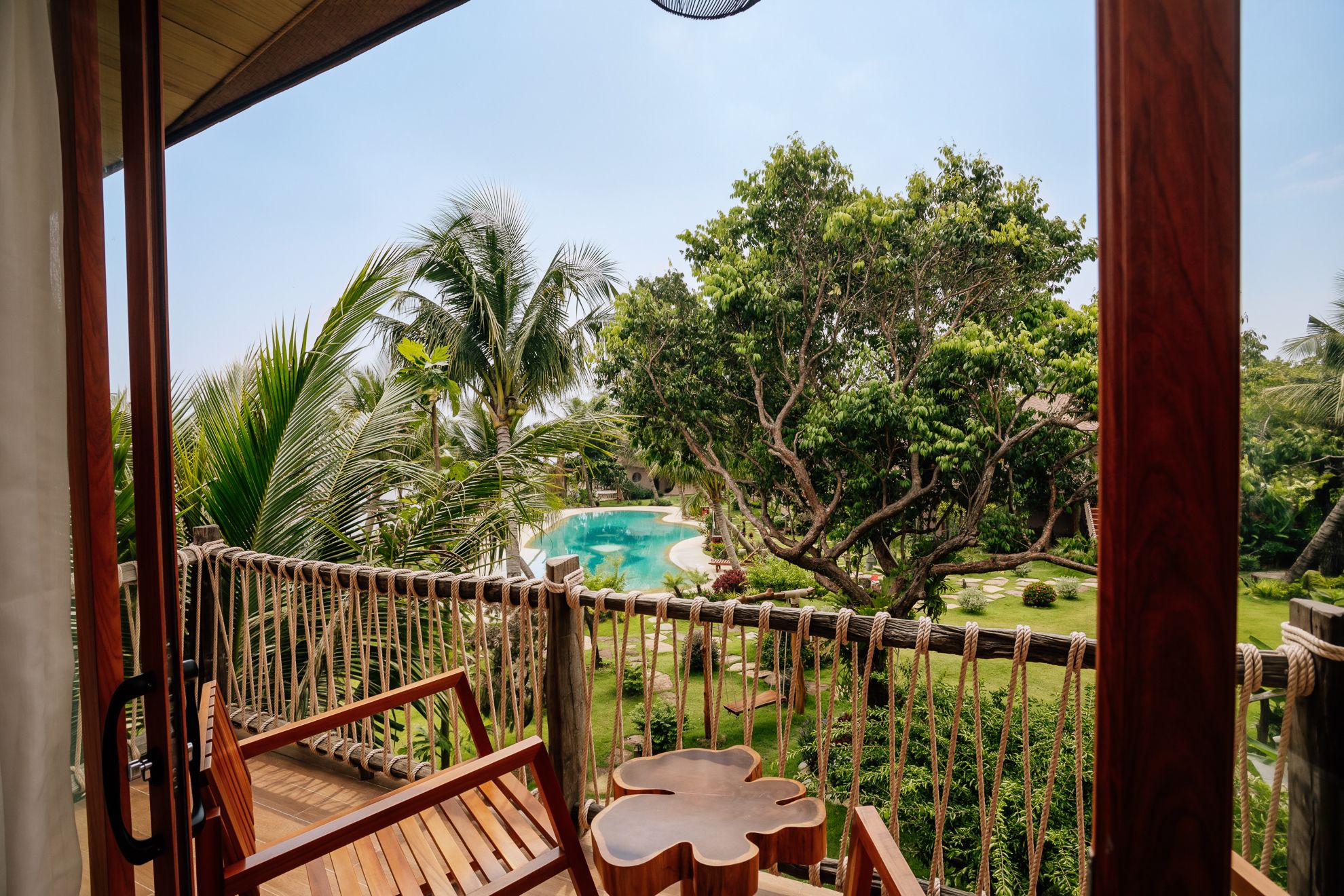 Deck de madeira com vista para uma piscina e vegetação exuberante.