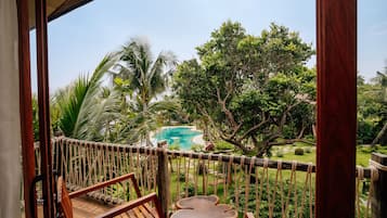 Deck de madeira com vista para uma piscina e vegetação exuberante.