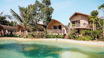 Um resort com várias acomodações no estilo de bangalô, piscina e vegetação tropical exuberante.
