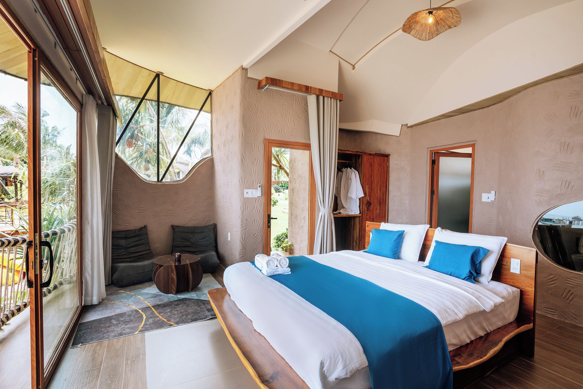 Quarto de hotel com uma cama grande, um espaço de estar pequeno e vista para o exterior.