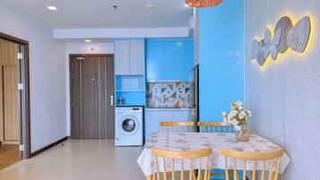 Uma cozinha moderna com armários azuis, uma máquina de lavar roupa e uma sala de jantar com mesa e cadeiras.