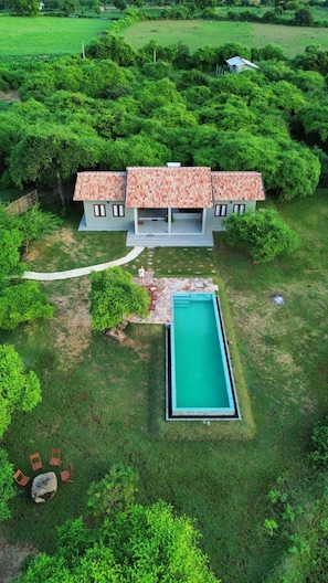 Uma casa de dois andares com telhado de telhas, piscina e jardim.
