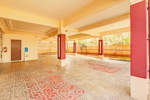 Um espaço amplo e interno com piso estampado, colunas e vista para o exterior.