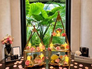 Uma exibição decorativa com velas, flores e um livro intitulado 'OCULUS' sobre uma mesa.