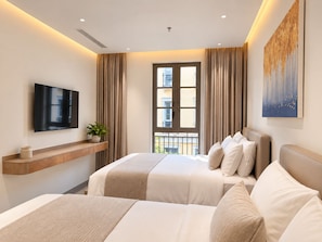 Quarto de hotel com duas camas, televisão fixada na parede, janela com cortinas e um quadro na parede.