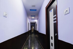 Um corredor com piso de mármore, uma porta com o símbolo de número e um interruptor de luz na parede.