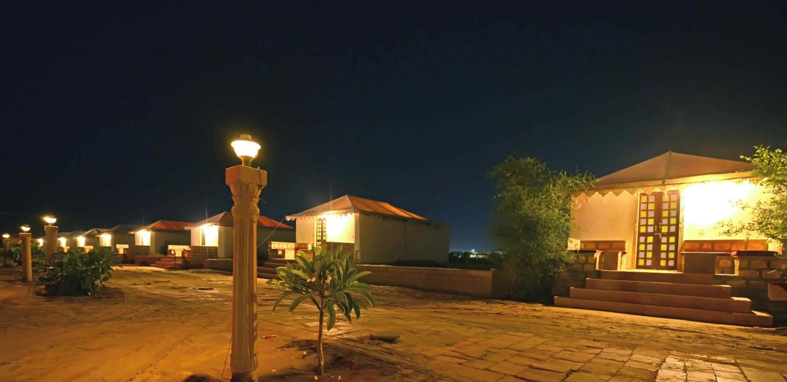 Um conjunto de edifícios com janelas iluminadas e um pátio pavimentado à noite.