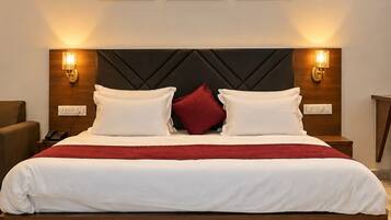 Quarto de hotel com uma cama grande, duas luminárias fixadas na parede e arte abstrata acima da cama.