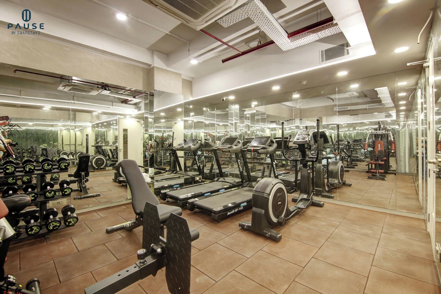 Academia com esteiras, máquinas de musculação e pesos livres.