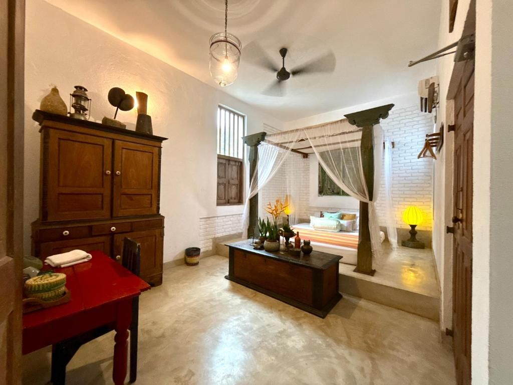 Quarto com cama, dossel, mesa de cabeceira e ventoinha no teto.