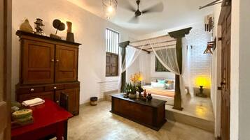 Quarto com cama, dossel, mesa de cabeceira e ventoinha no teto.