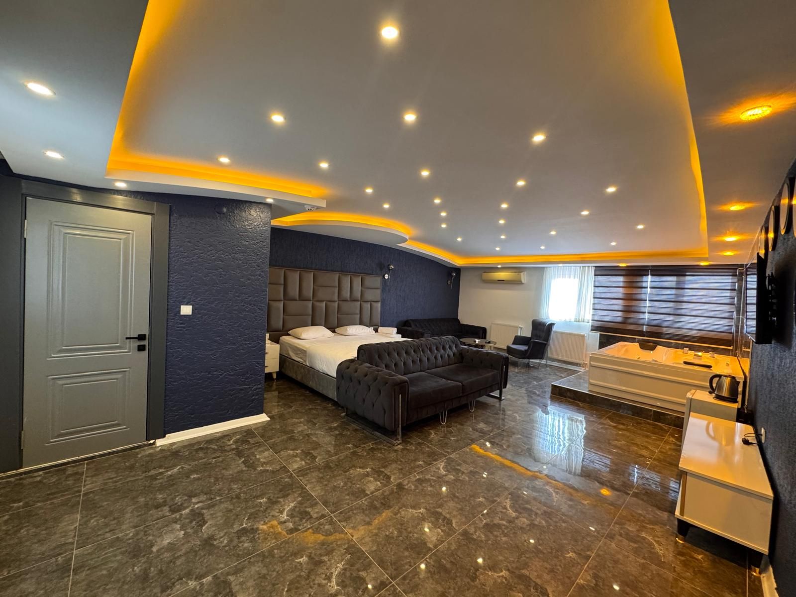 Quarto moderno com uma cama grande, um sofá, uma escrivaninha e uma banheira.