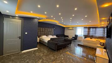 Quarto moderno com uma cama grande, um sofá, uma escrivaninha e uma banheira.