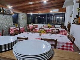 Um restaurante com várias mesas postas, com pratos, copos e talheres.