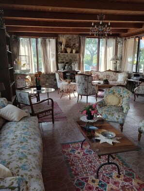 Uma sala de estar acolhedora com móveis estampados floralmente, um candelabro e vista para o exterior.
