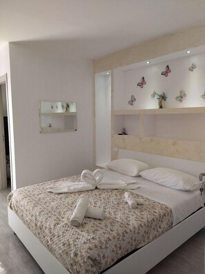 Quarto moderno com uma cama grande, espelho na mesa de cabeceira e decoração de borboletas na parede.