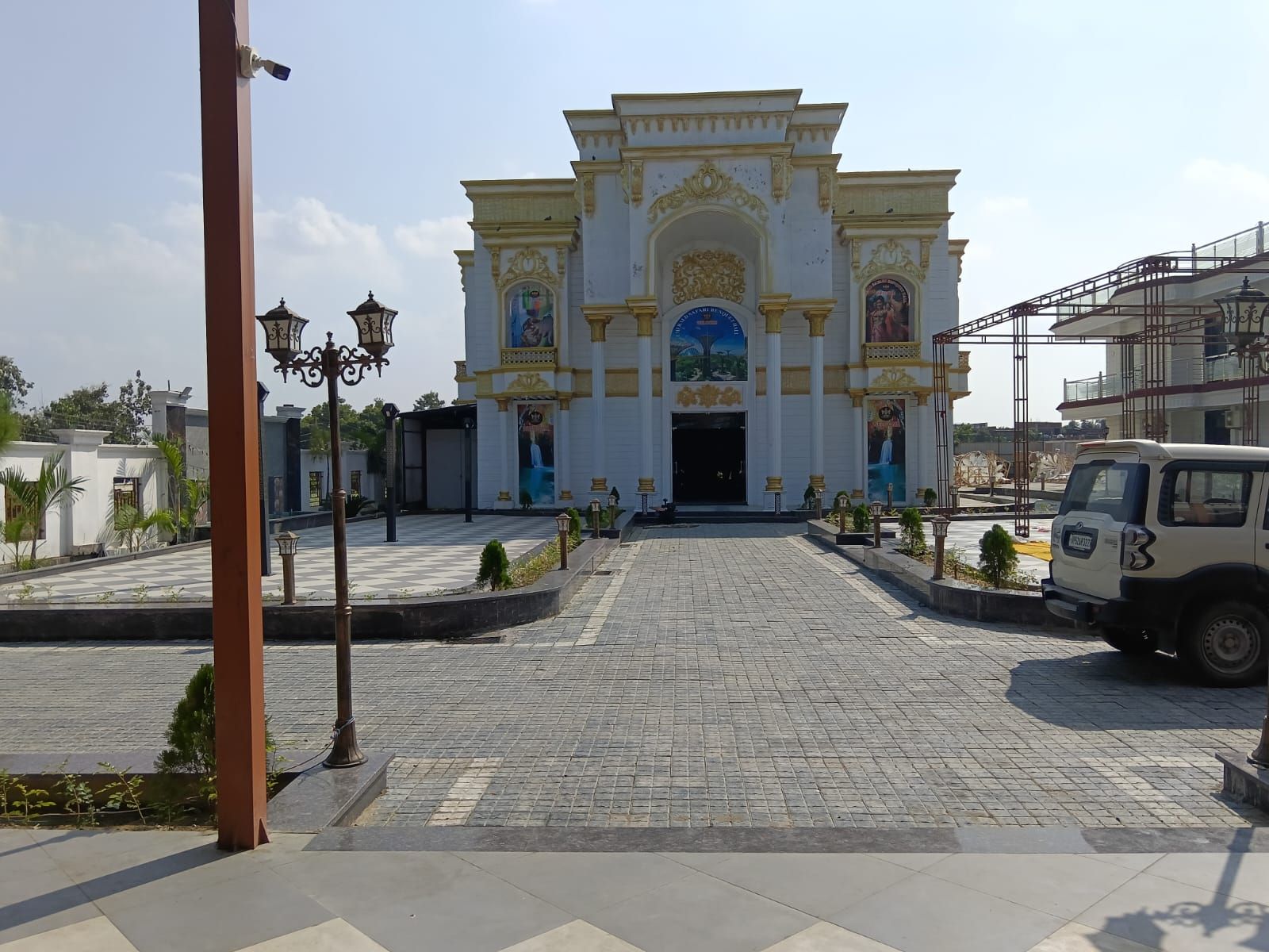 Um edifício com entrada central, pátio pavimentado e um veículo estacionado.