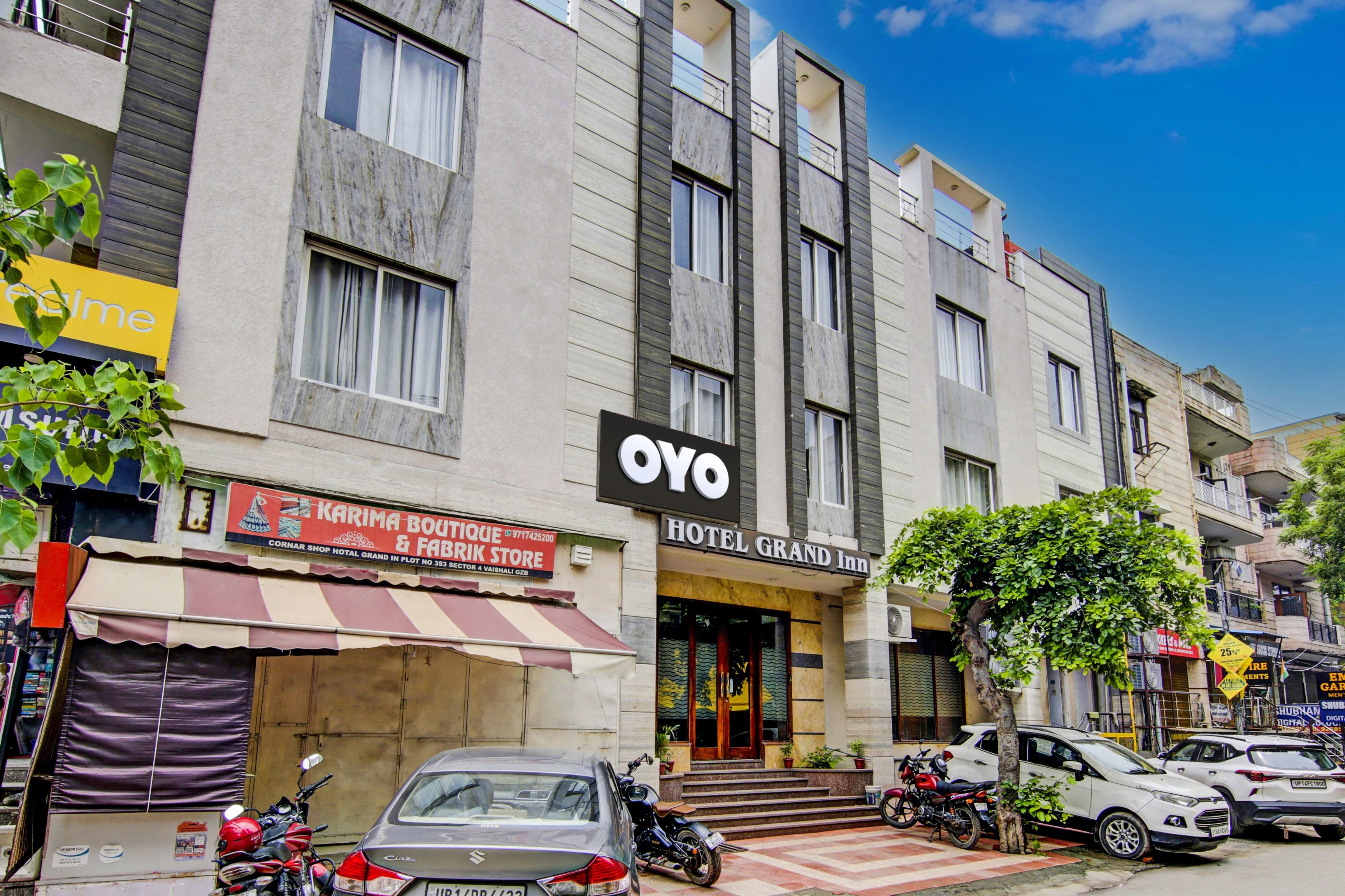 Hotel com fachada moderna, entrada visível e placa indicando uma loja de artigos de moda e tecidos.