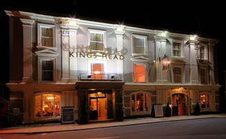Um edifício histórico com estilo arquitetônico clássico, apresentando uma entrada imponente com a placa 'Kings Head'.