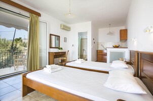 Quarto de hotel com duas camas, varanda, banheiro e cozinha compacta.