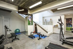 Academia com equipamentos de exercícios, esteira e escada.