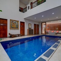 Piscina com um banco de madeira, um mural e uma porta de vidro que dá para uma área de estar.