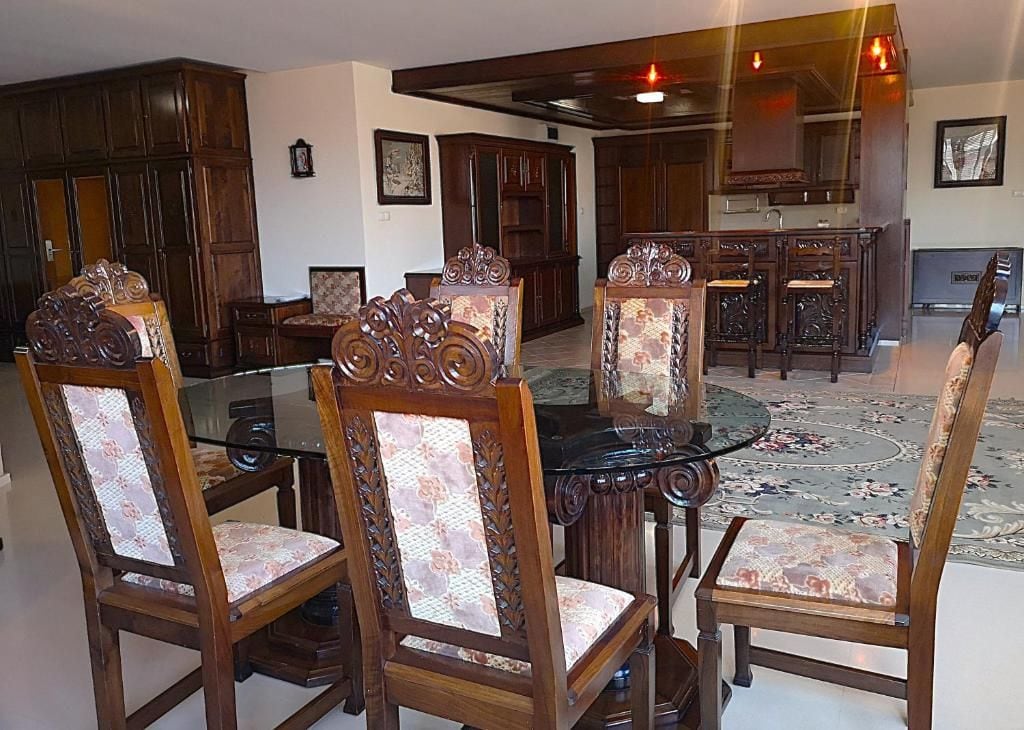 Uma sala de jantar com uma mesa de vidro rodeada por cadeiras decoradas com estofados estampados.