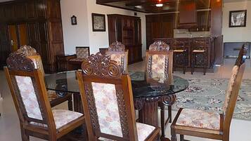 Uma sala de jantar com uma mesa de vidro rodeada por cadeiras decoradas com estofados estampados.