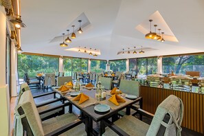 Restaurante com várias mesas, cadeiras e iluminação pendente.