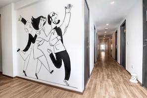 Um corredor longo com piso de madeira e uma parede com mural em preto e branco.