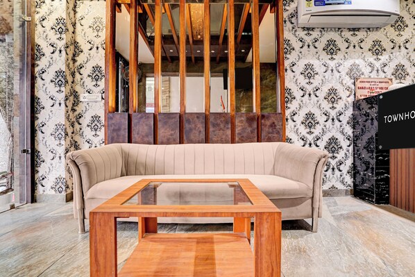 Uma sala de estar moderna com um sofá bege, uma mesa de centro de madeira e papel de parede estampado.