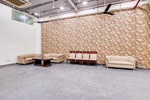 Quarto com parede de pedra, um sofá, uma mesa de centro e um conjunto de cadeiras.