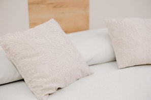 Uma cama com dois travesseiros, um com padrão floral e outro liso.