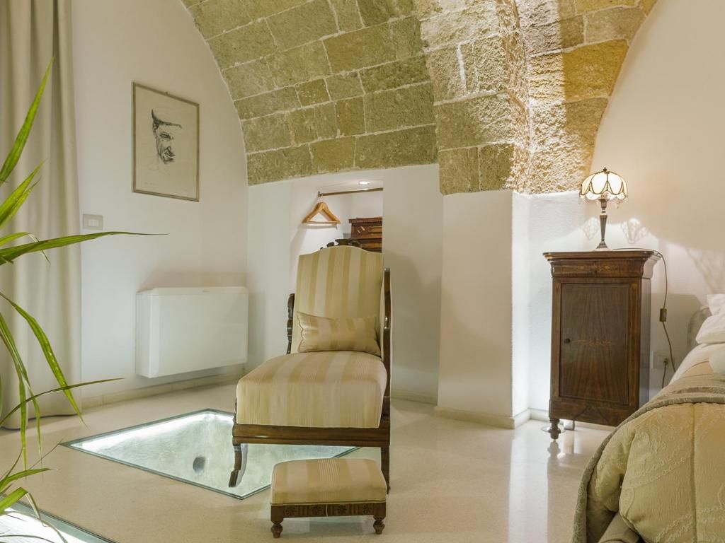 Quarto com teto alto, uma cadeira de madeira, um armário e um abajur pendente.
