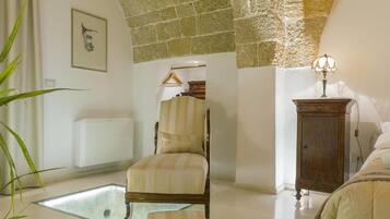 Quarto com teto alto, uma cadeira de madeira, um armário e um abajur pendente.